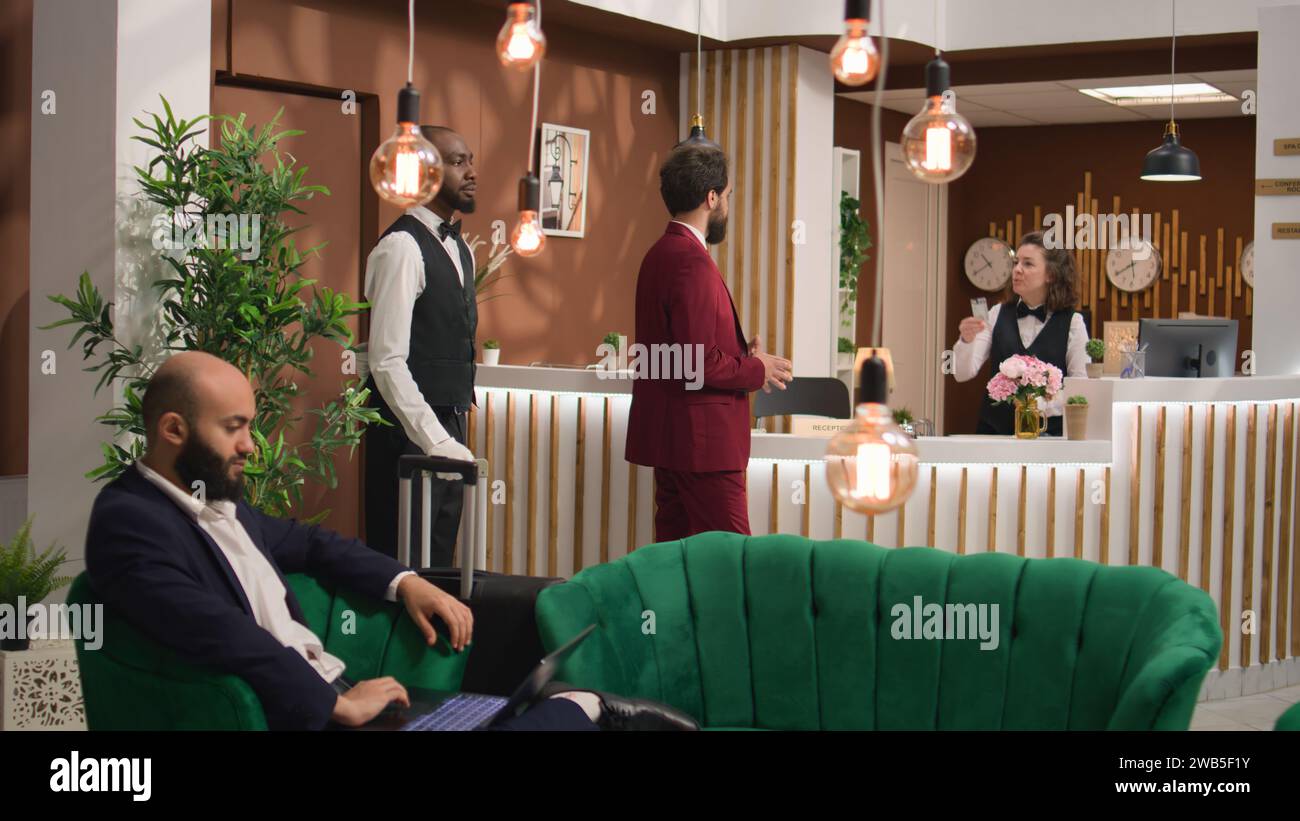 Hotel staff hands out key card for white collar worker, ensuring ...