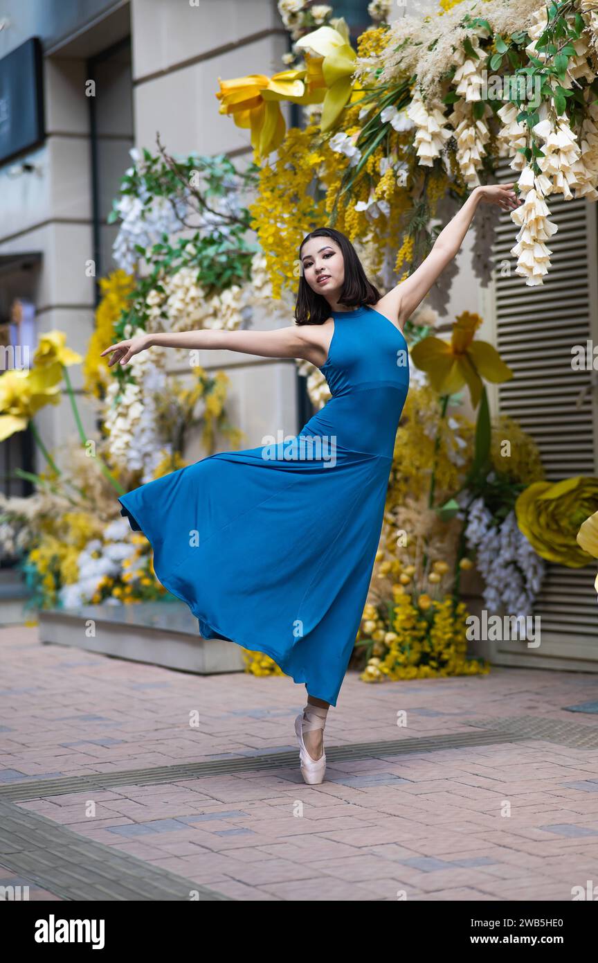 Beautiful Asian ballerina dances against the background of a building decorated with flowers ...