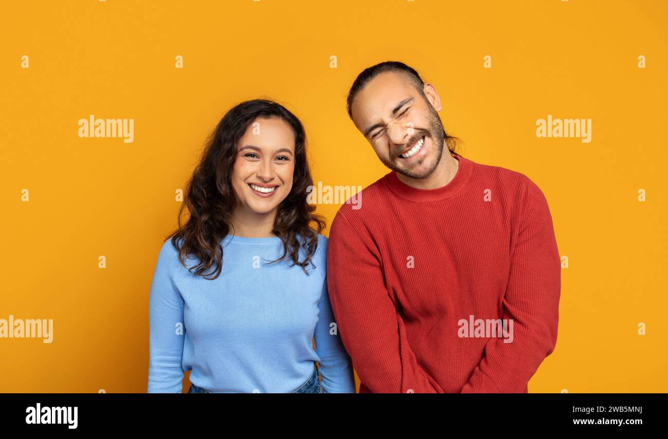 Cute millennial couple posing together on orange background Stock Photo ...
