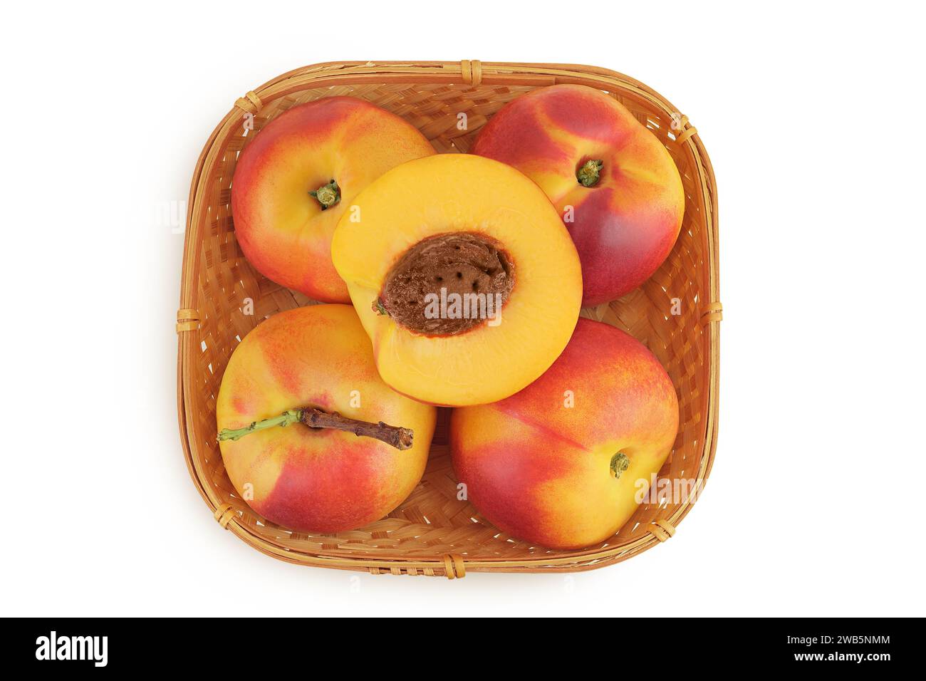 Ripe nectarine fruit with half in a wicker basket isolated on white ...