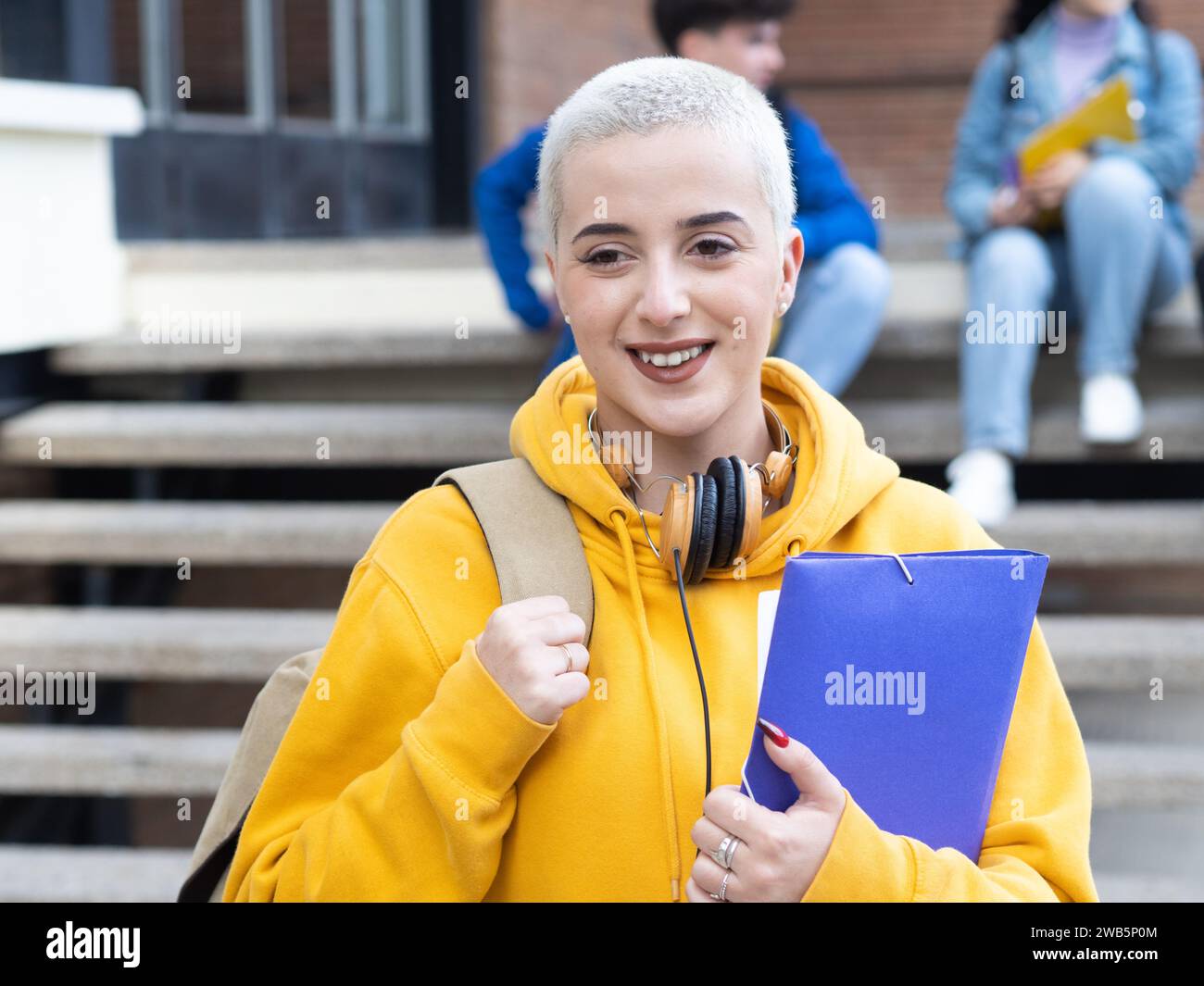 Portrait of a young alternative student with short hair on a campus ...