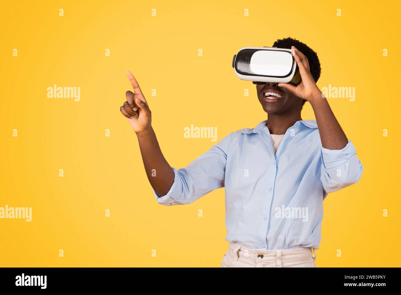Glad teen black lady student in VR glasses point finger at free space ...