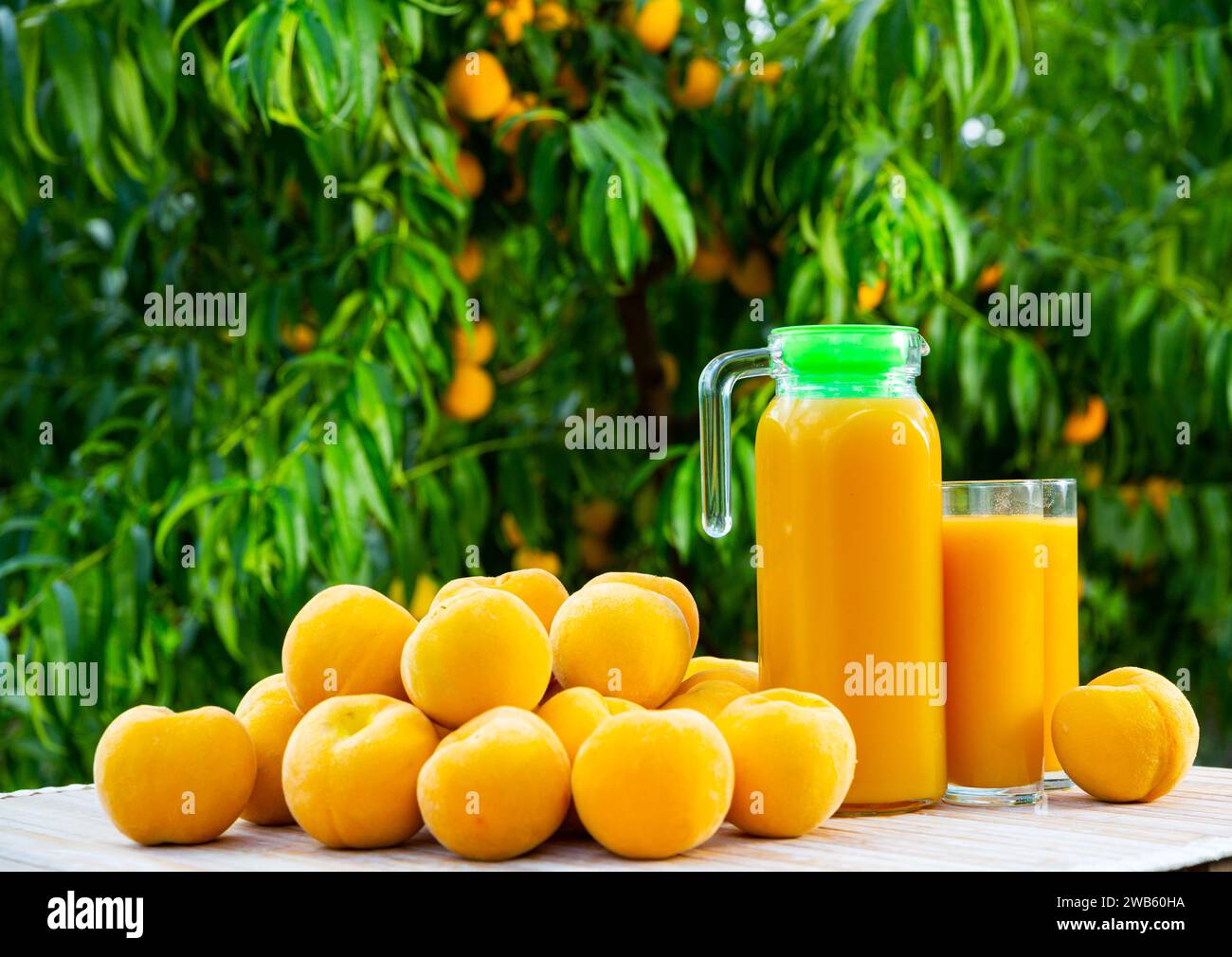 Jug of freshly squeezed peaches juice with peaches in an outdoor ...