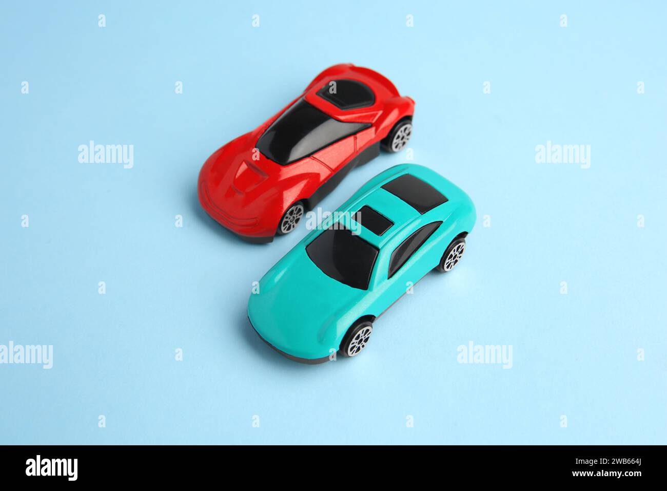 Two bright cars on light blue background, above view. Children`s toys ...