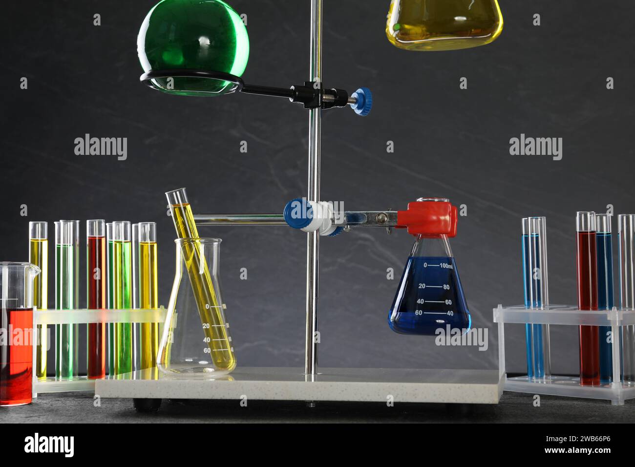 Retort stand and laboratory glassware with liquids on table against ...