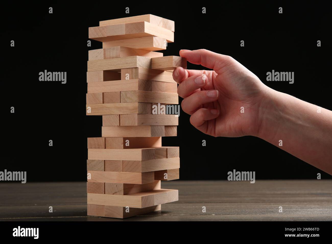 Woman playing Jenga at table against black background, closeup Stock ...