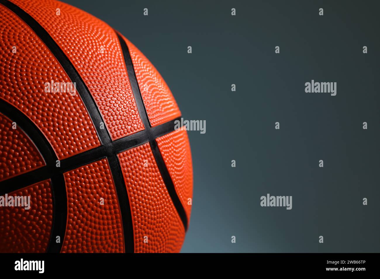 One orange basketball ball on dark grey background, closeup. Space for ...
