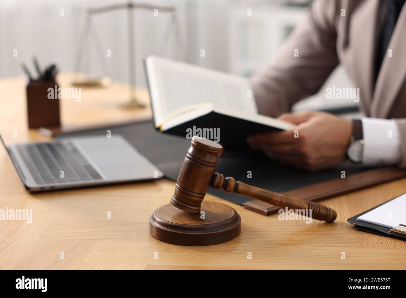 Lawyer reading book at table in office, focus on gavel Stock Photo - Alamy