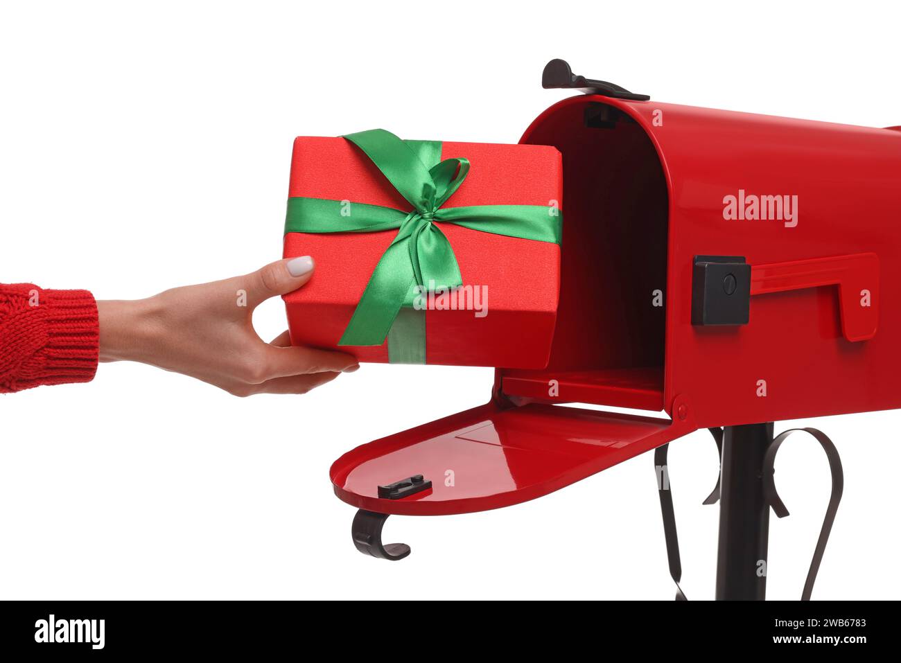 Woman putting Christmas gift into mailbox on white background, closeup ...