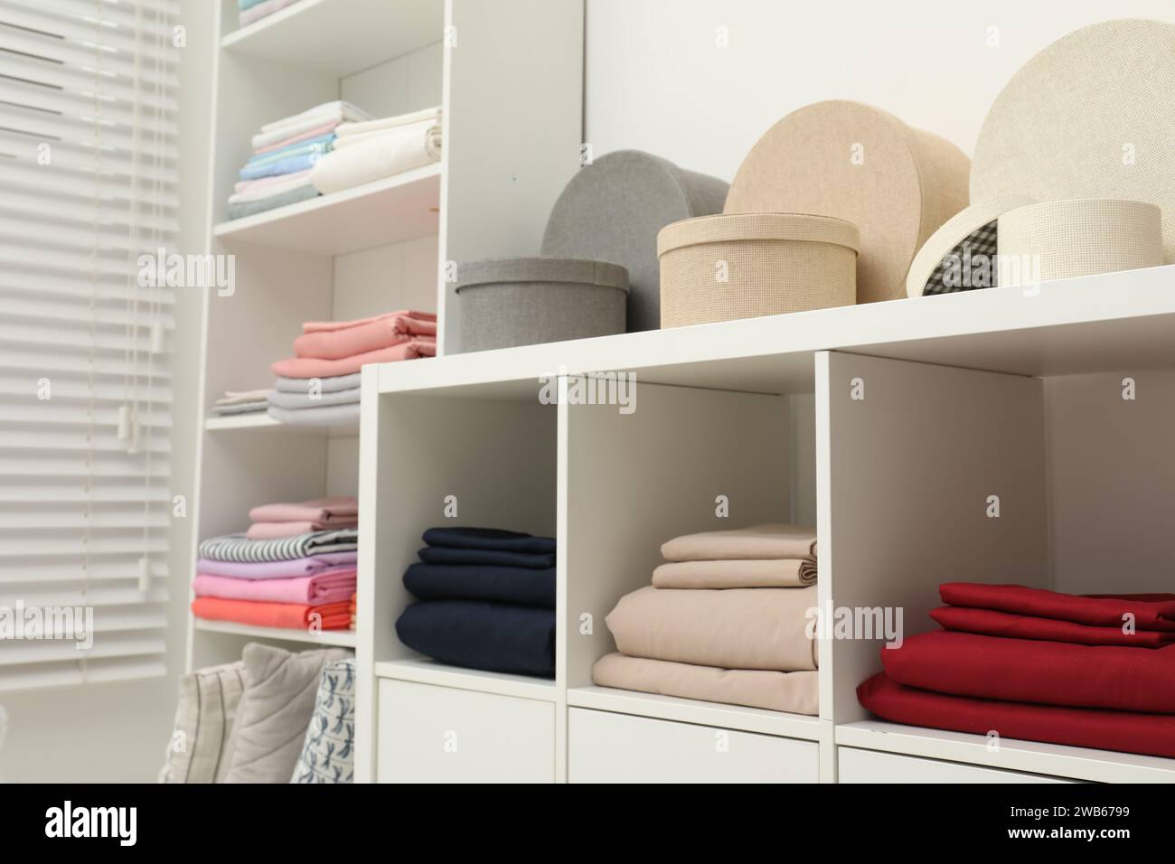 Different colorful bed linens and decorative boxes on display in home ...