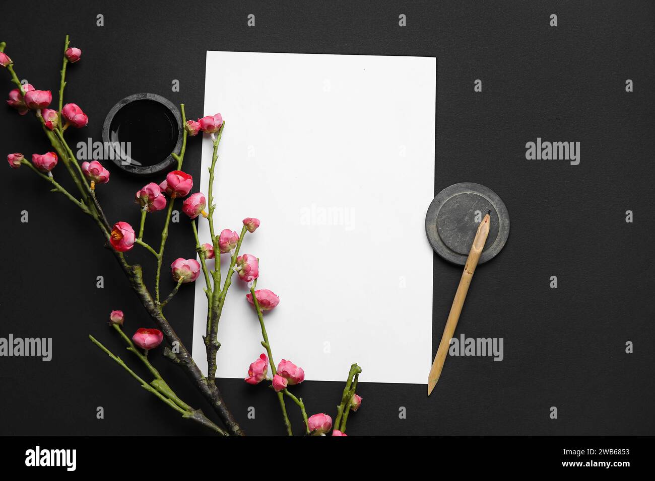 Composition with blank sheet of paper, ink, nib pen and blooming branch ...