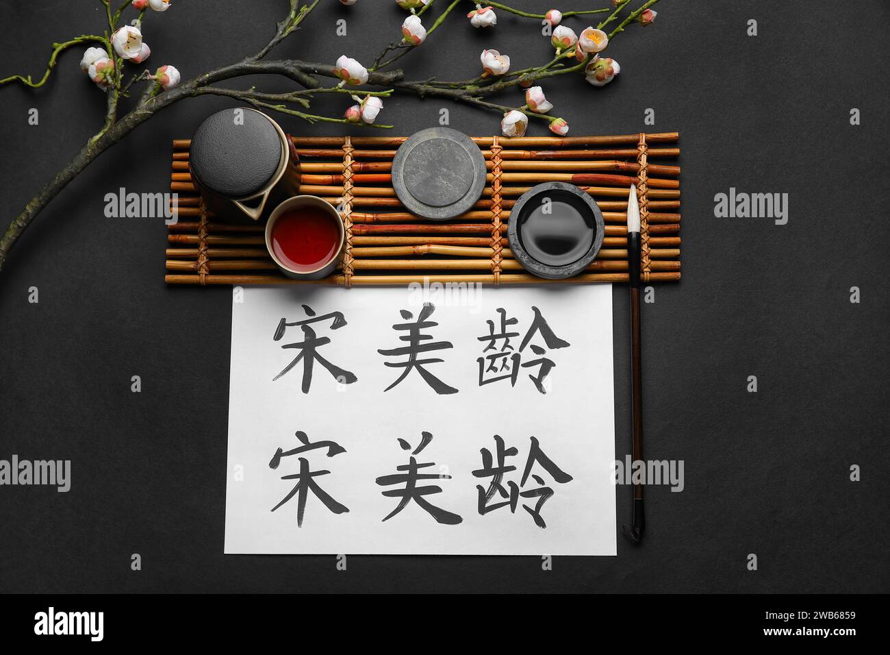 Paper sheet with Asian hieroglyphs, brush, ink, cup of tea and blooming ...