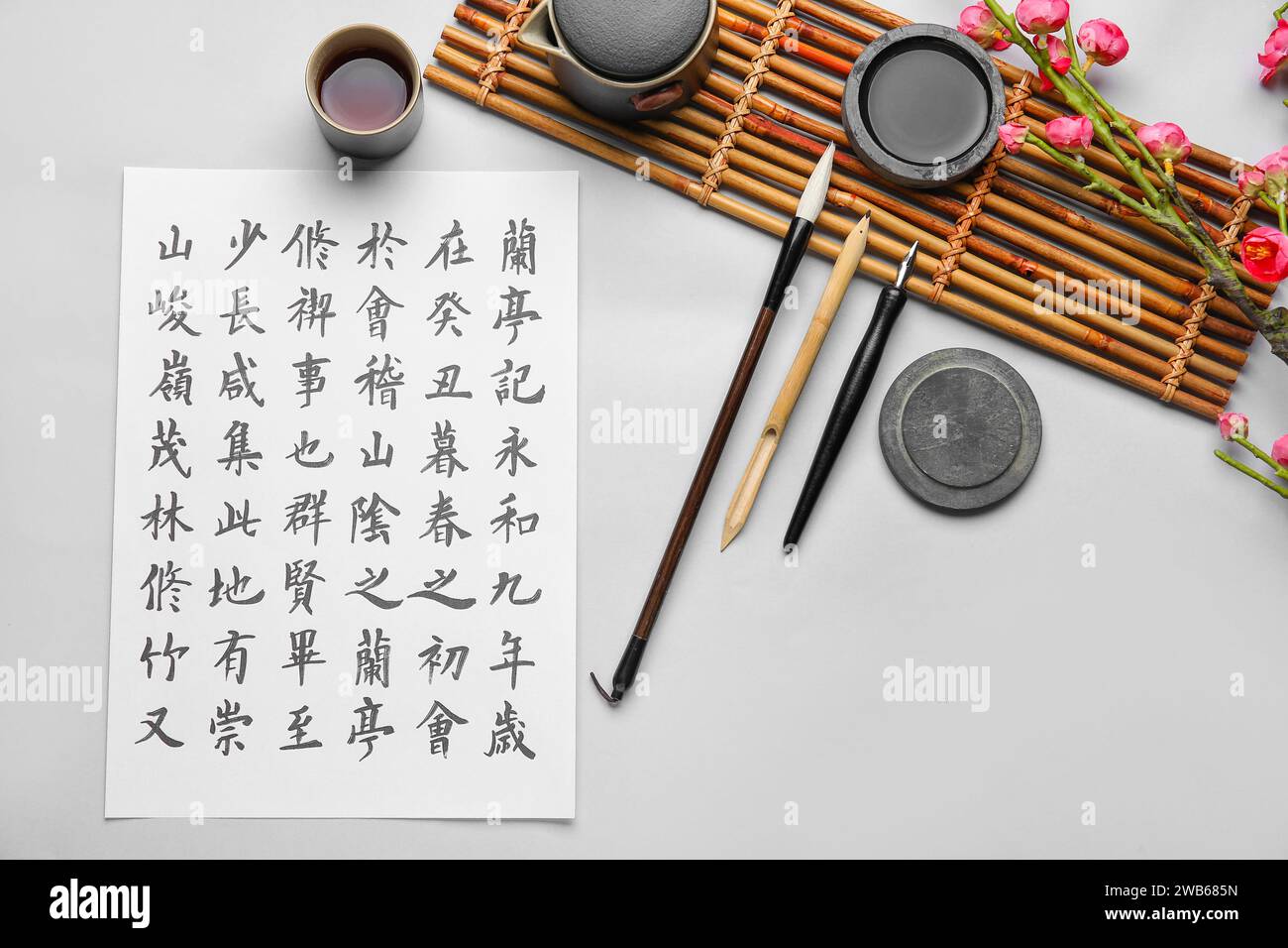 Paper sheet with Asian hieroglyphs, calligraphy supplies and cup of tea ...