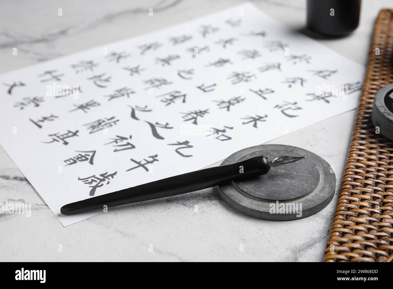 Paper sheet with Asian hieroglyphs and nib pen on light background ...