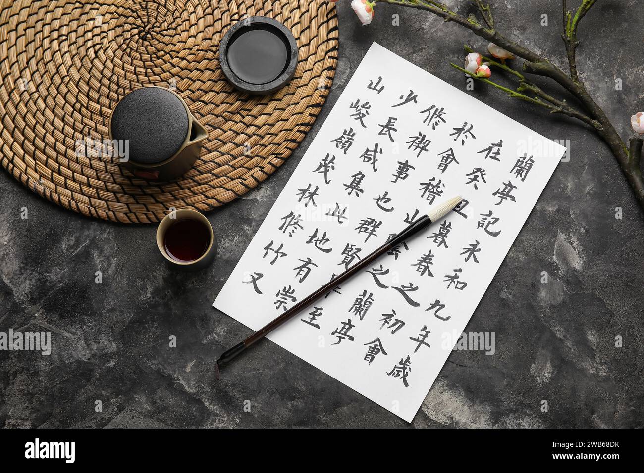 Paper sheet with Asian hieroglyphs, brush, ink and cup of tea on grunge ...
