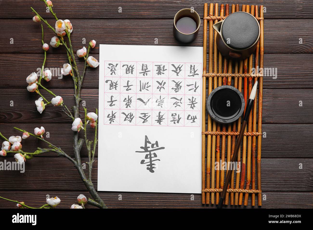 Paper sheet with Asian hieroglyphs, ink, brush, cup of tea and blooming ...