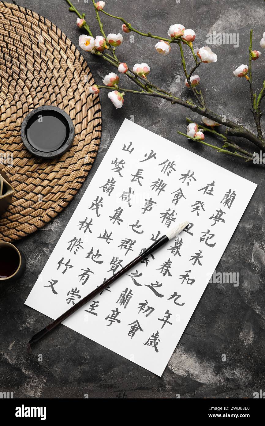 Paper sheet with Asian hieroglyphs, brush, ink and blooming branch on ...