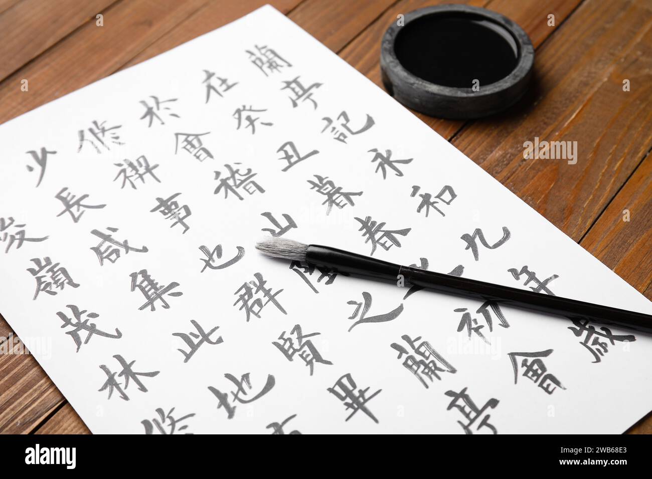 Paper sheet with Asian hieroglyphs, brush and ink on wooden background ...