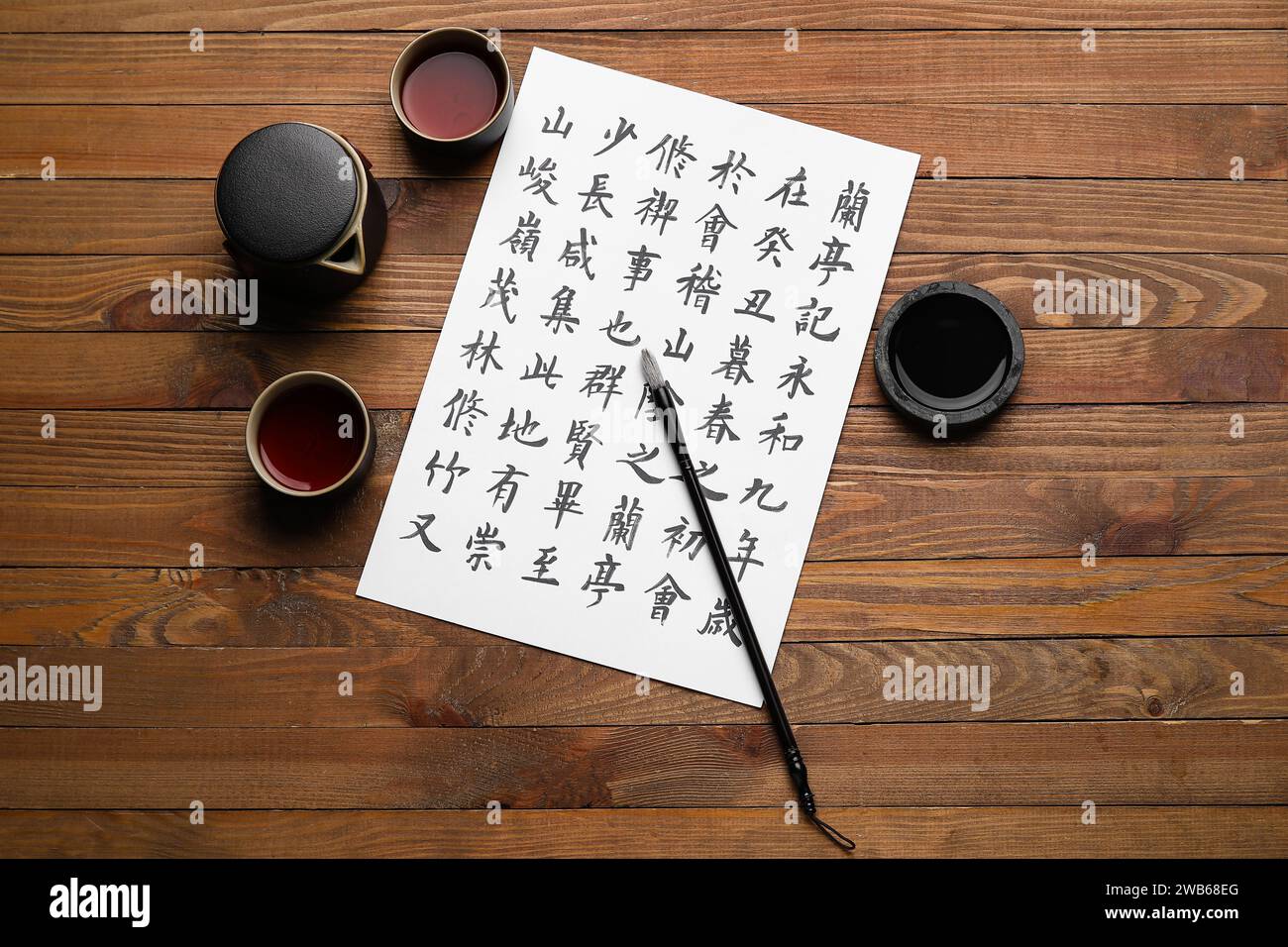 Paper sheet with Asian hieroglyphs, cups of tea, brush and ink on ...
