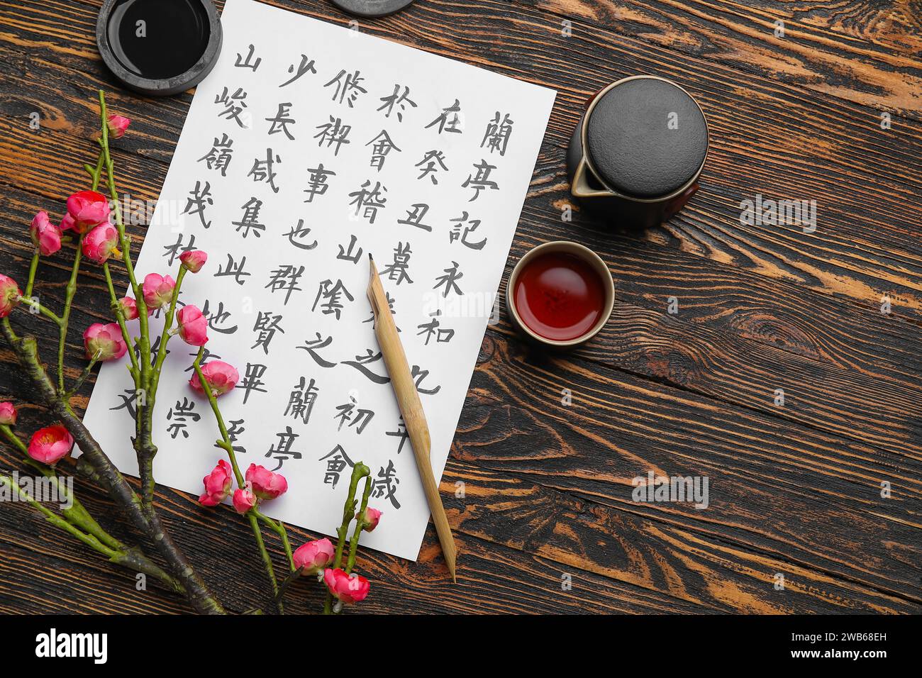 Paper sheet with Asian hieroglyphs, nib pen, ink, cup of tea and ...
