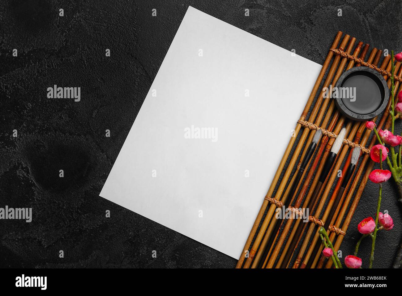 Composition with blank sheet of paper, bamboo mat, brushes and ink on ...