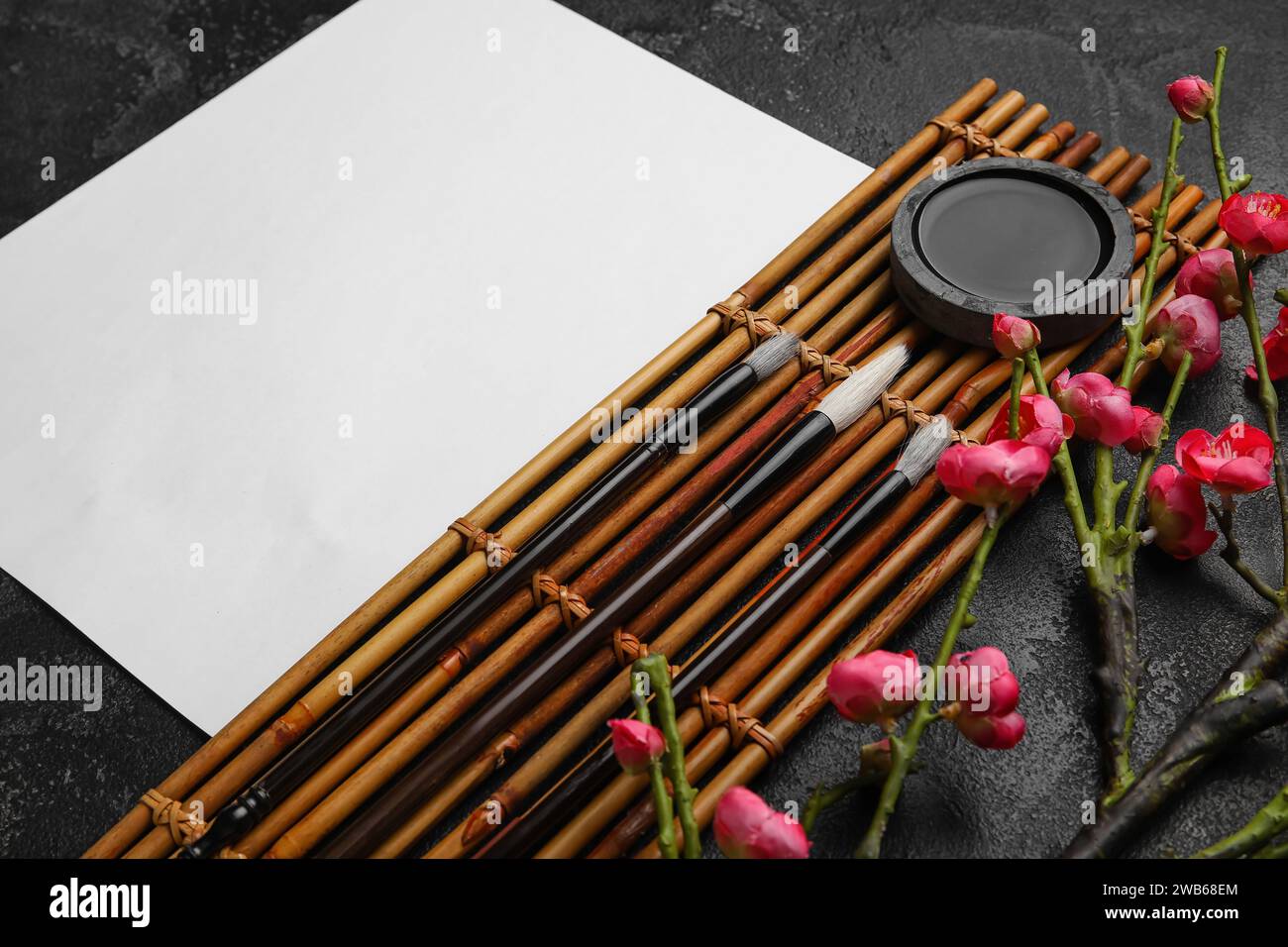 Composition with blank sheet of paper, bamboo mat, brushes, ink and ...