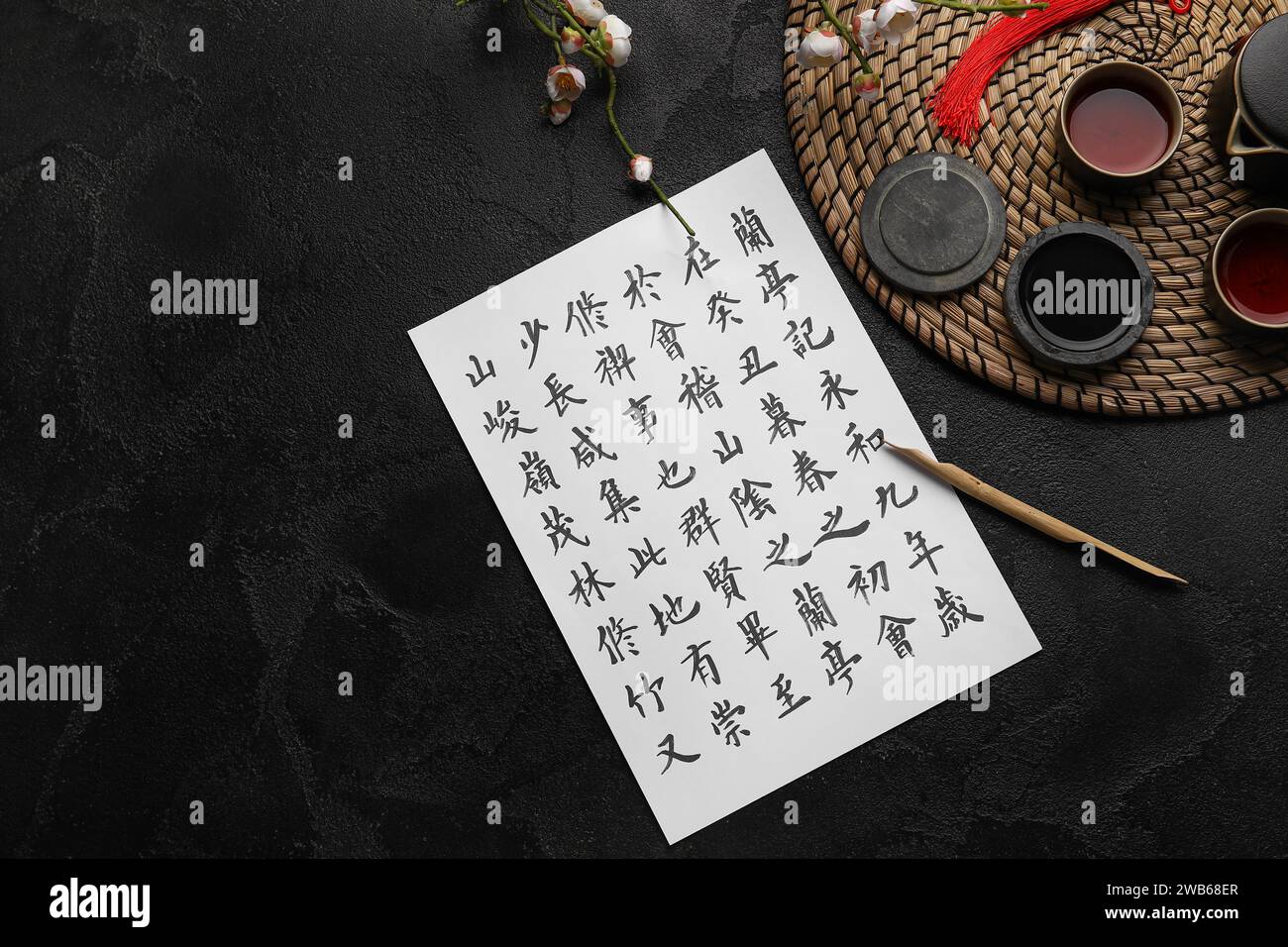 Paper sheet with Asian hieroglyphs, ink, nib pen and cups of tea on ...