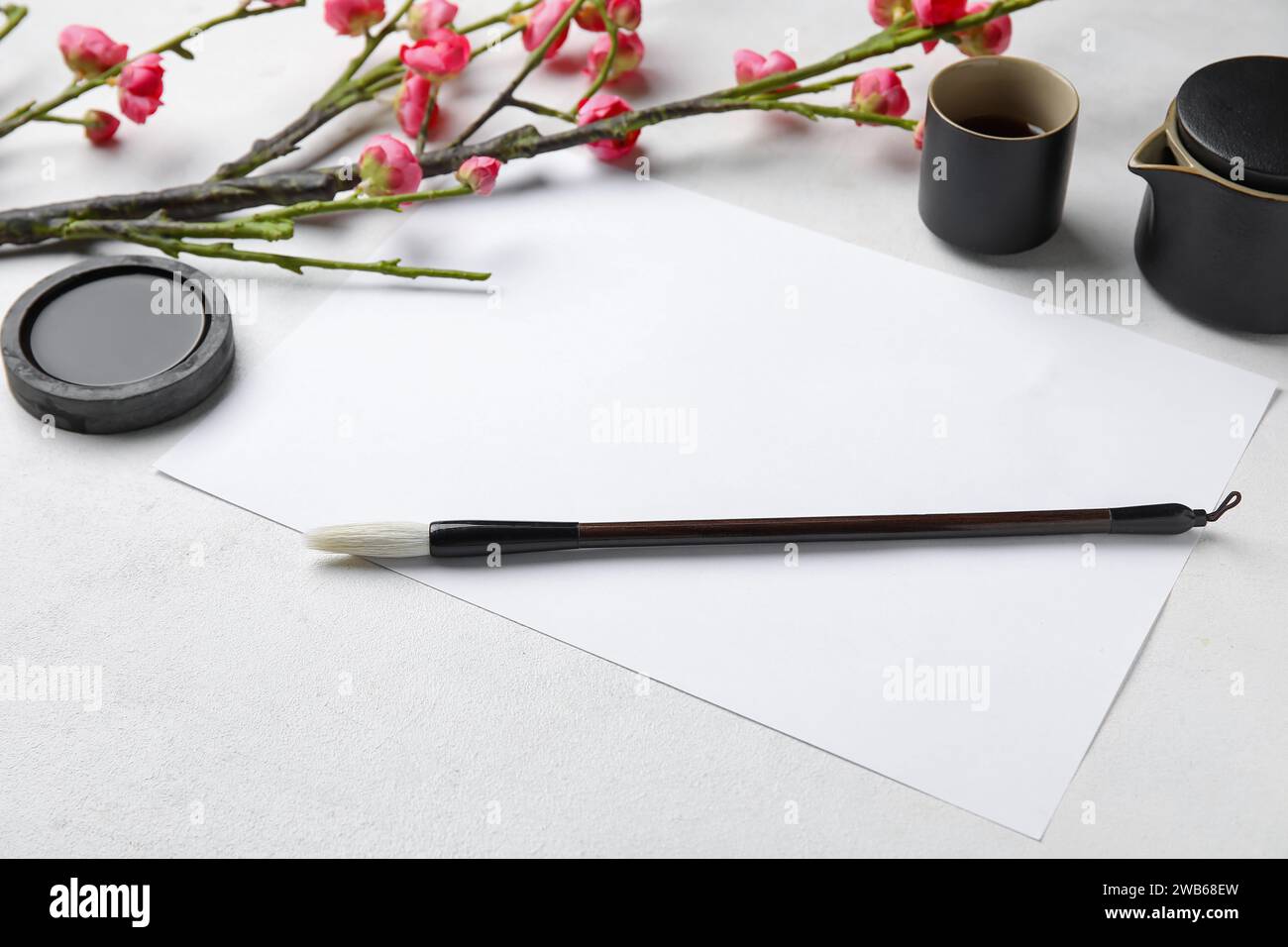 Composition with blank sheet of paper, ink, brush, cup of tea and ...