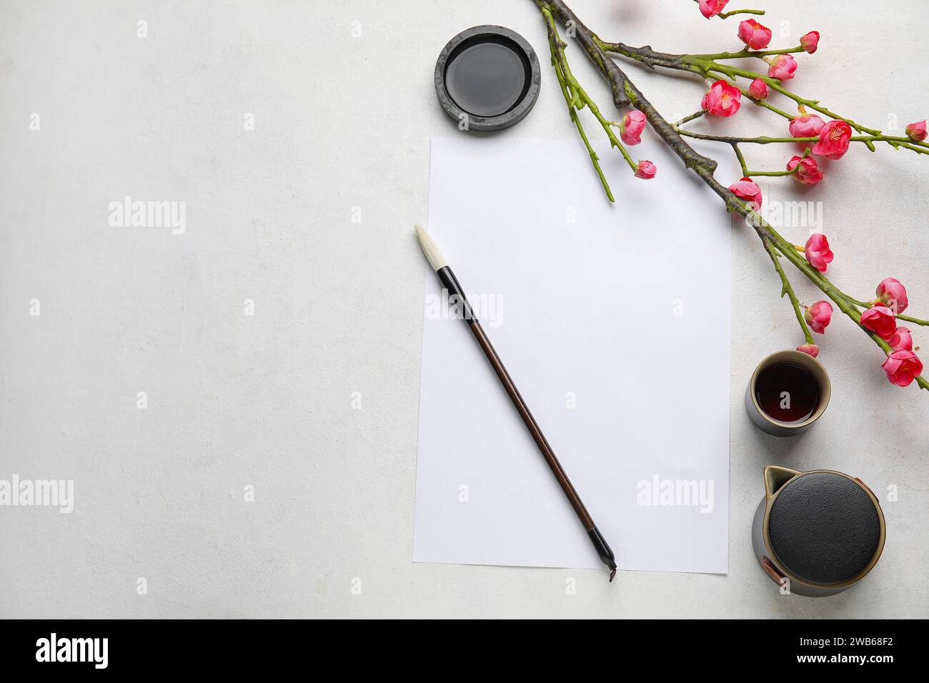 Composition with blank sheet of paper, ink, brush and blooming branch ...