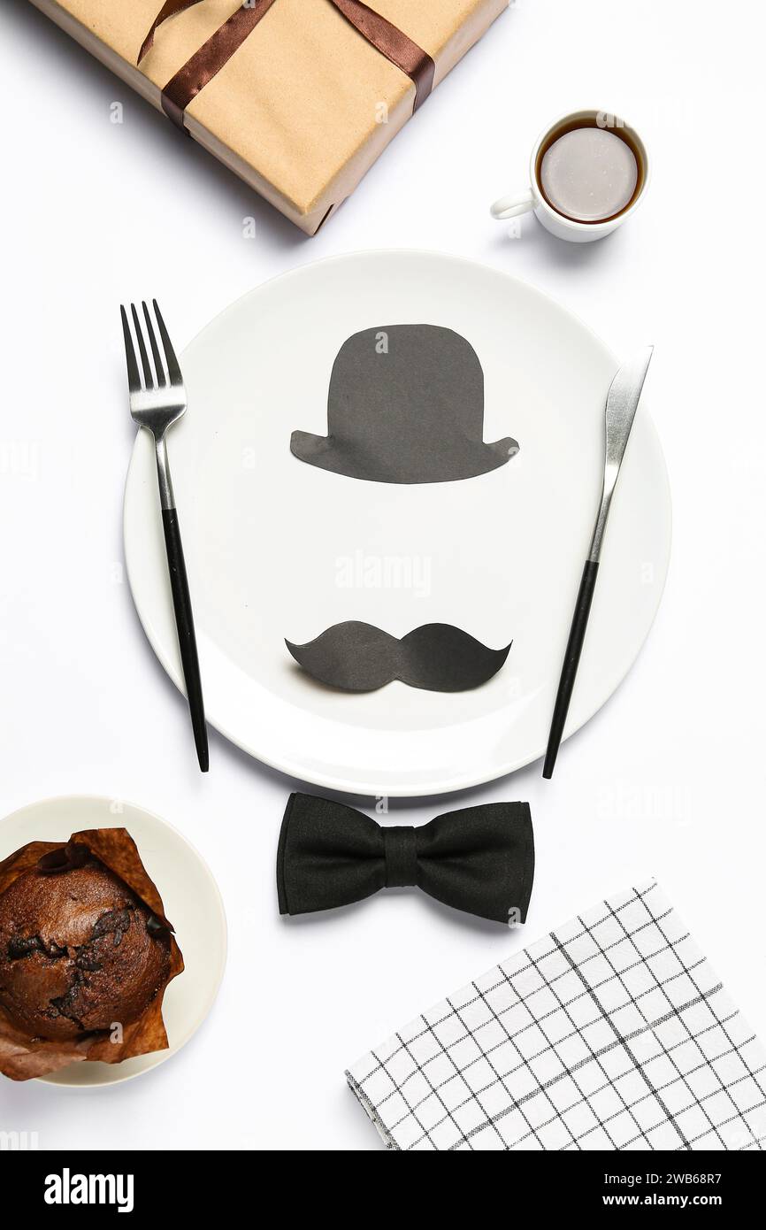 Table setting with paper mustache, hat and gift on white background ...