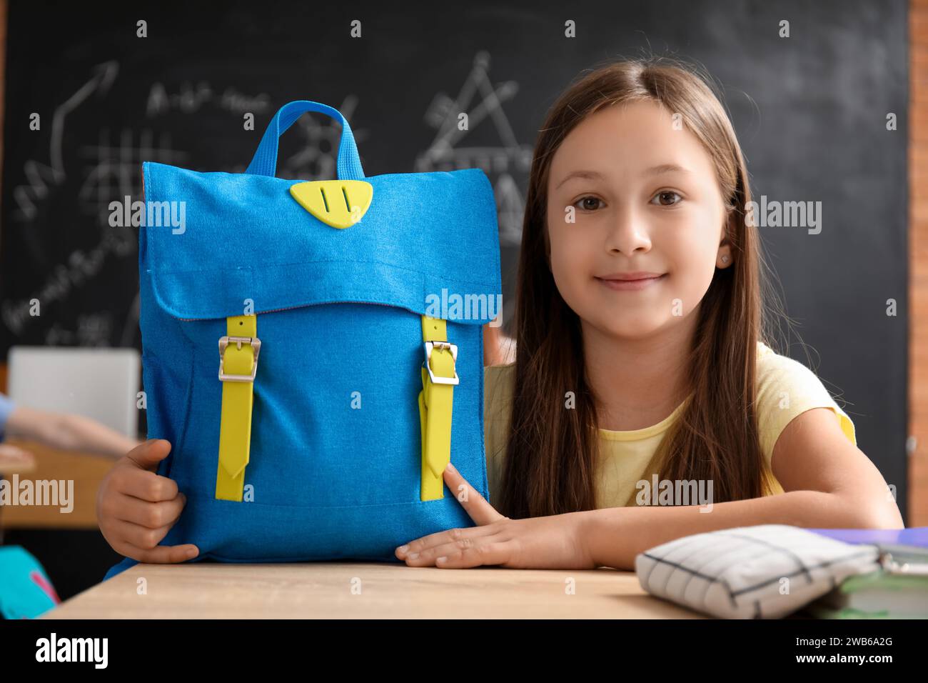 Little girl with backpack in classroom Stock Photo - Alamy