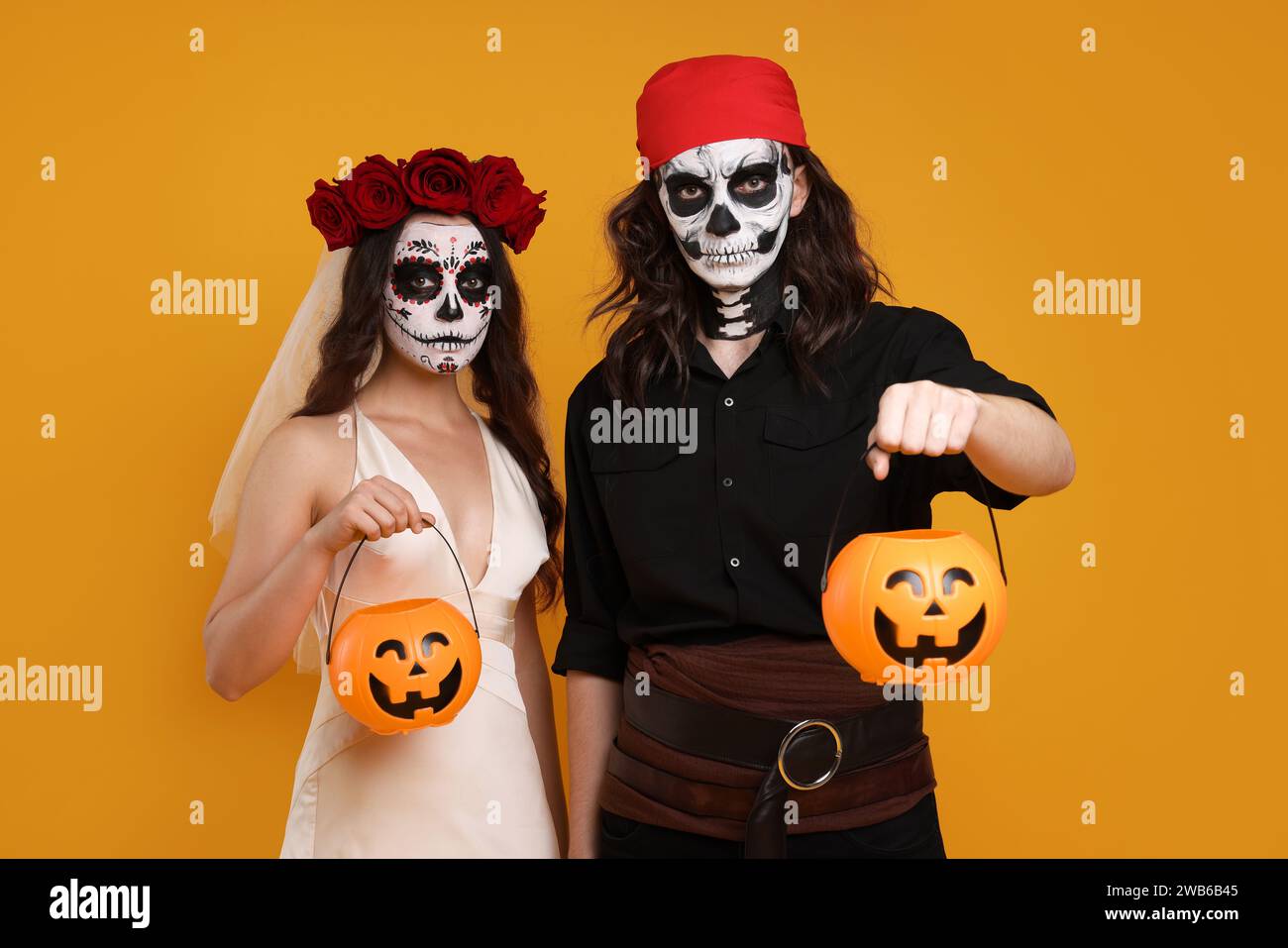Couple in scary bride and pirate costumes with pumpkin buckets on ...