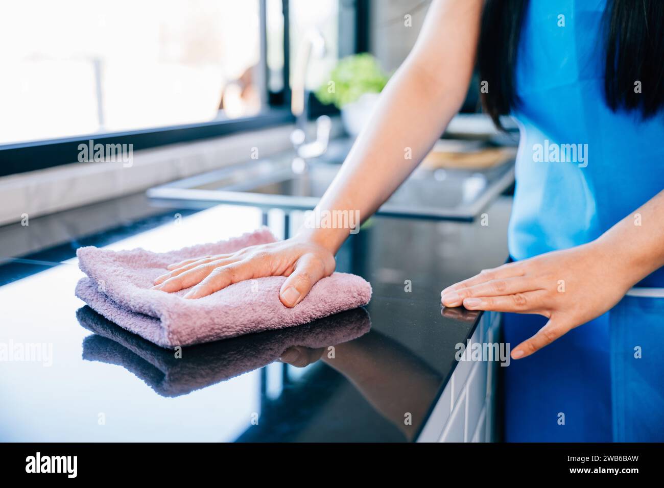 A cheerful housewife ensures safety and hygiene by wiping her kitchen ...