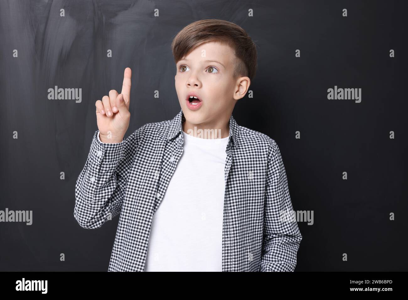 Back to school. Surprised boy pointing upwards near chalkboard Stock ...