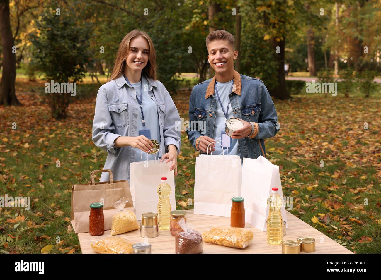 Portrait of volunteers packing food products at table in park Stock ...
