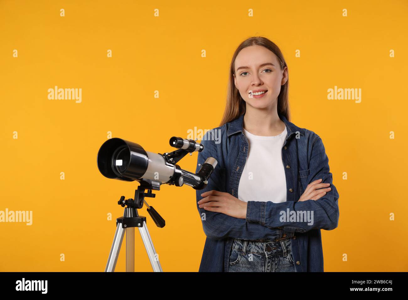 Happy astronomer with telescope on orange background, space for text ...