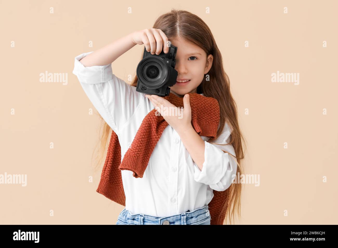 Cute little photographer with camera on beige background. Opposite Day ...