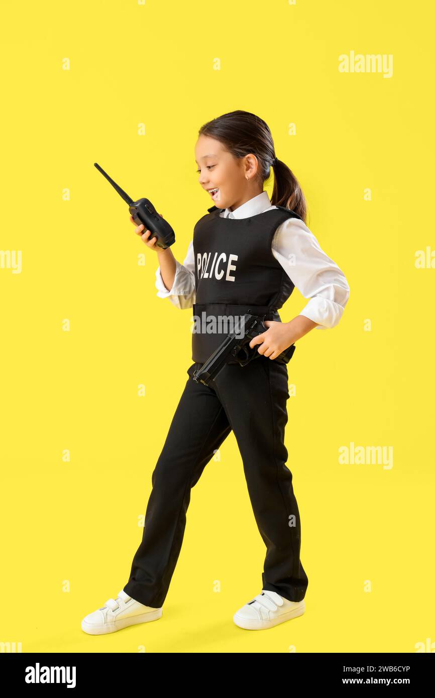 Cute little police officer with radio transmitter and gun on yellow ...
