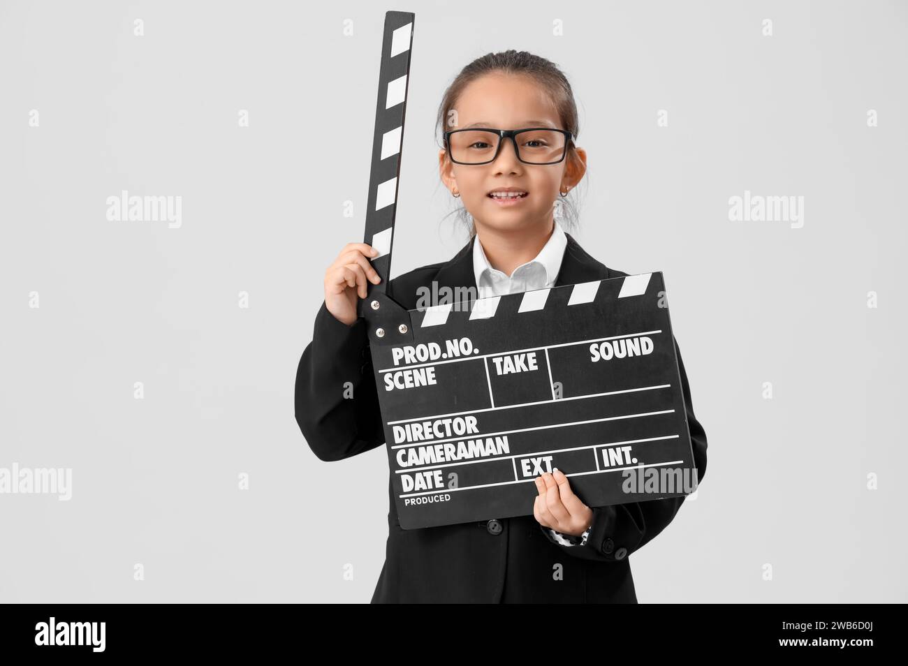 Cute little movie director with clapperboard on light background ...