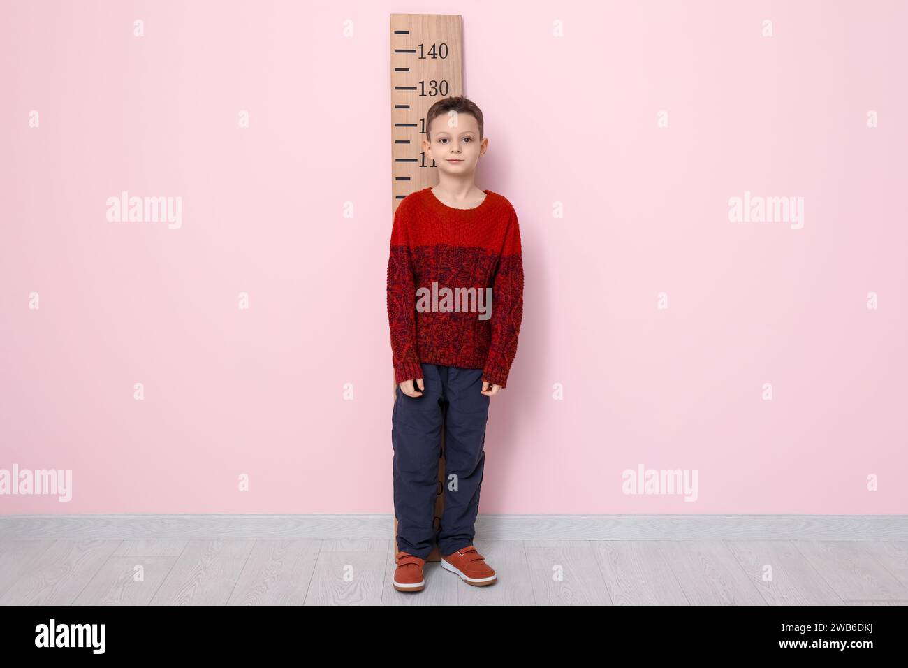 Cute little boy measuring height near pink wall Stock Photo - Alamy