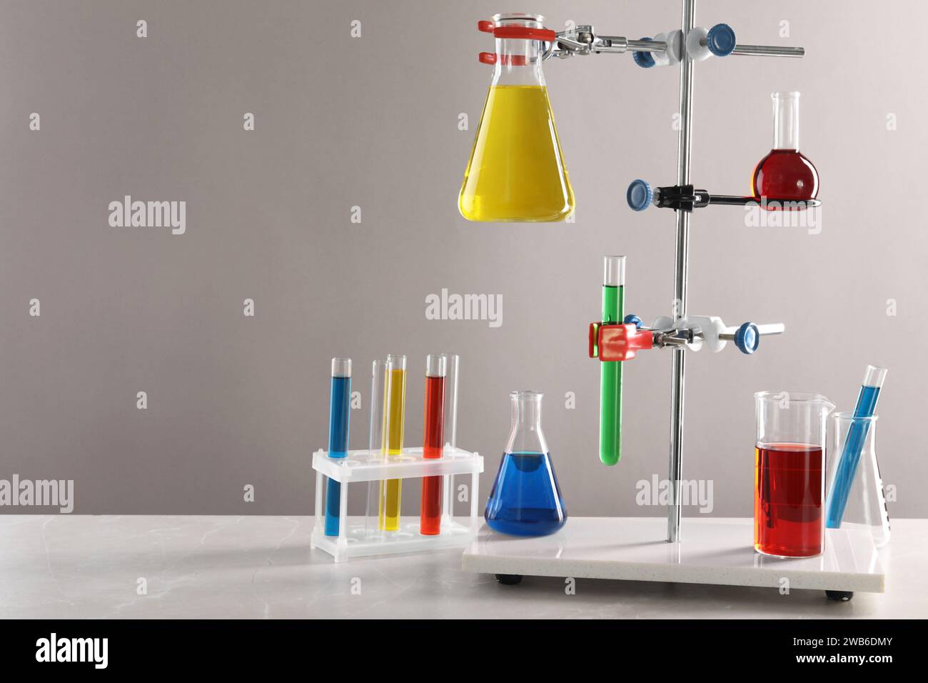 Retort stand and laboratory glassware with liquids on table against ...