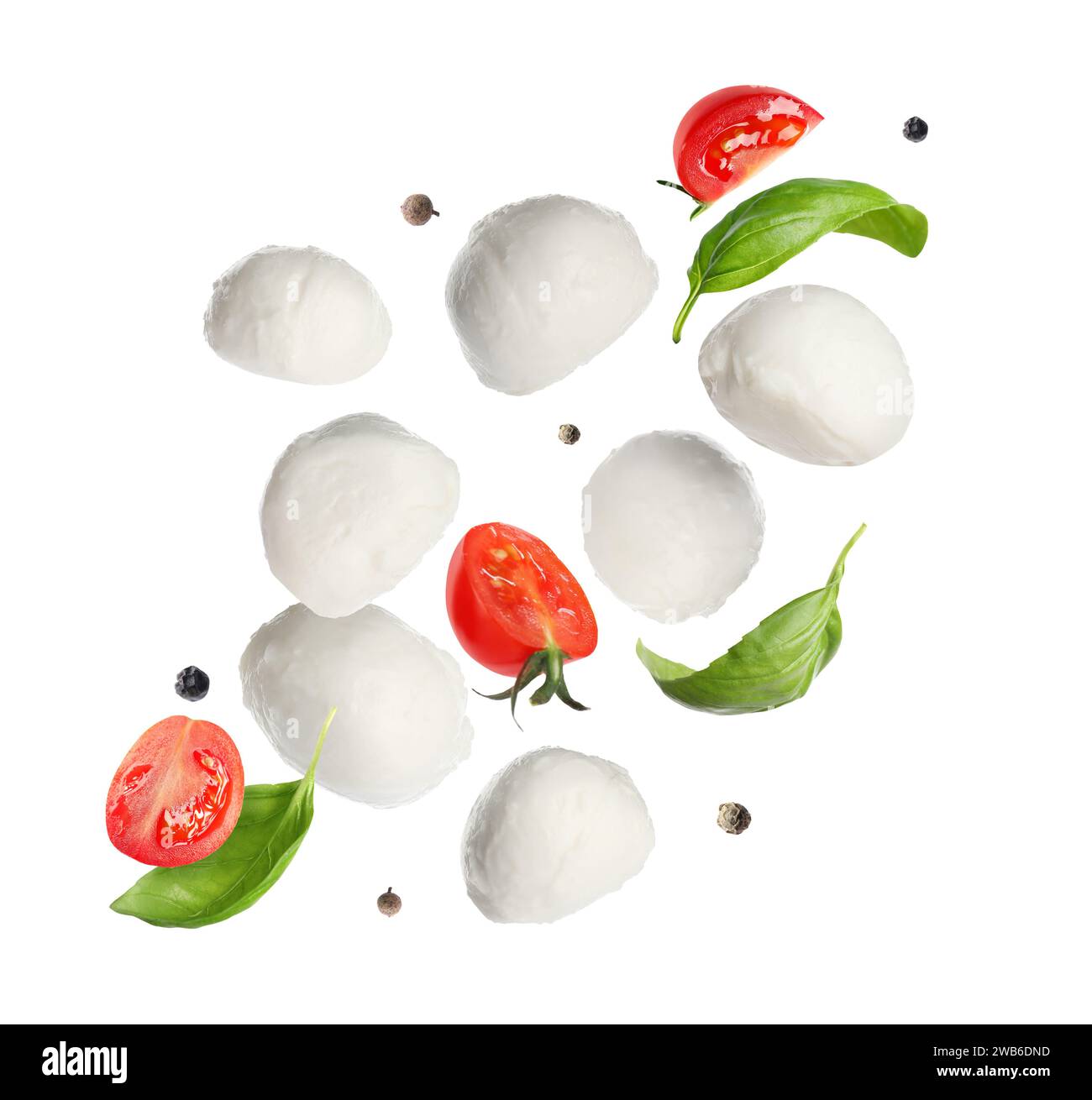 Mozzarella balls, cut tomatoes, basil leaves and peppercorns falling on ...