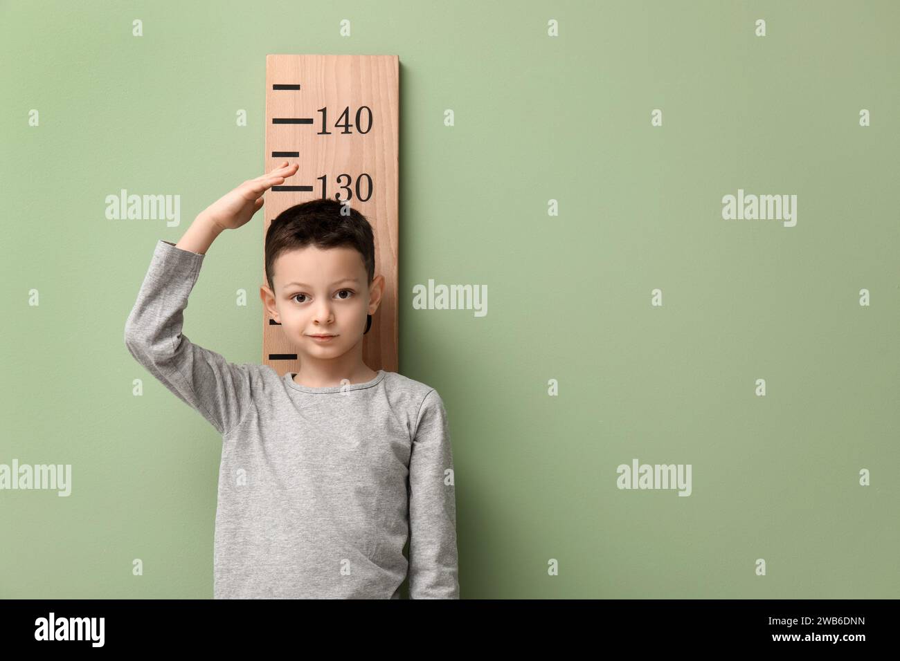 Cute little boy measuring height on green background Stock Photo - Alamy