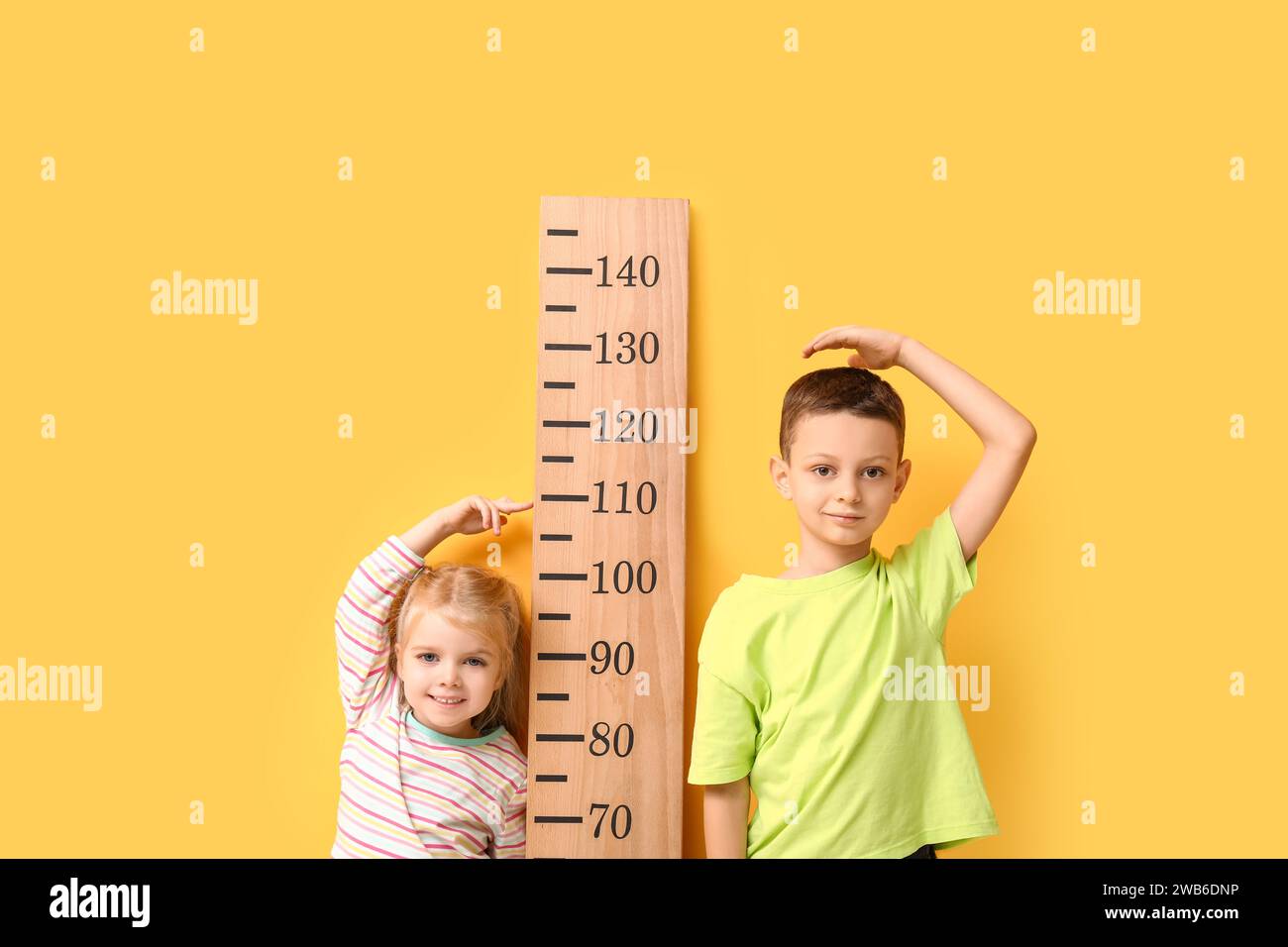 Cute little children measuring height on yellow background Stock Photo ...