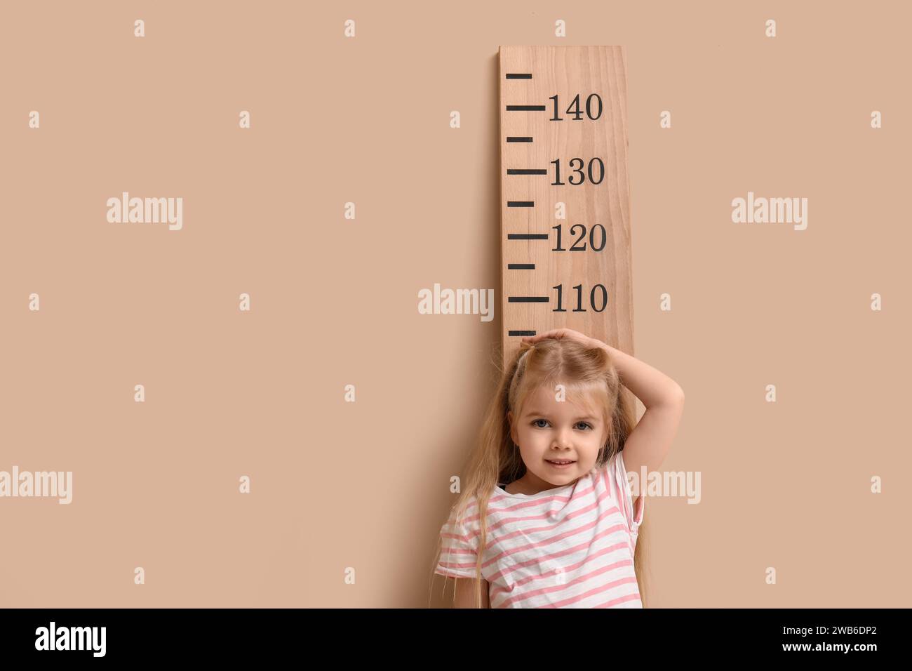 Cute little girl measuring height on beige background Stock Photo - Alamy