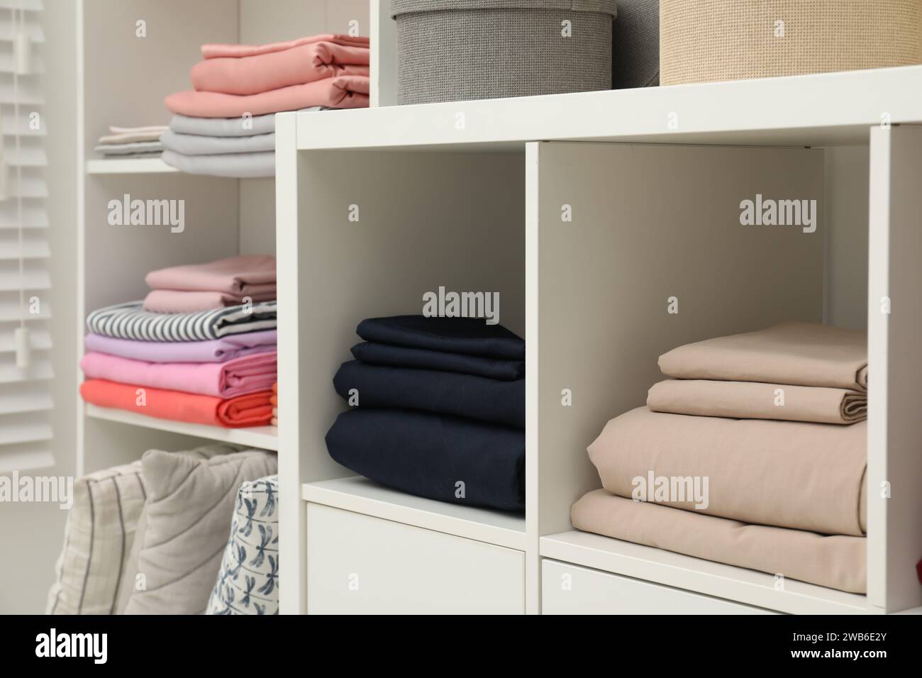 Different colorful bed linens and decorative boxes on display in home ...