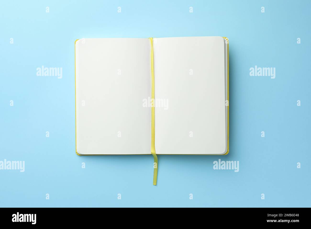 Open notebook with blank pages on light blue background, top view ...