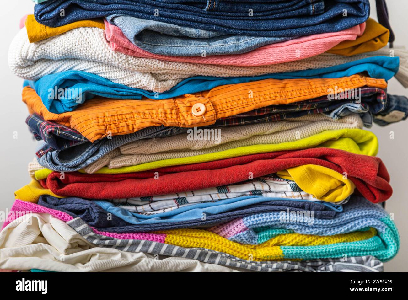 A very tall stack of folded colored clothes for charity, washing ...