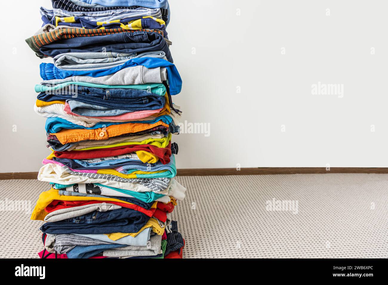 A very tall stack of folded colored clothes for charity, washing ...