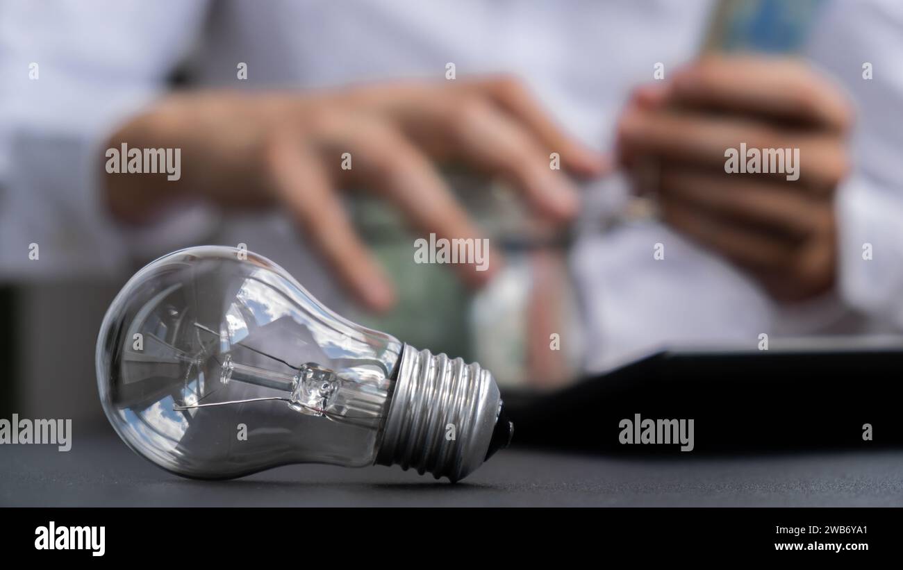 Electric light bulb. Man hands counting expenses on electricity ...